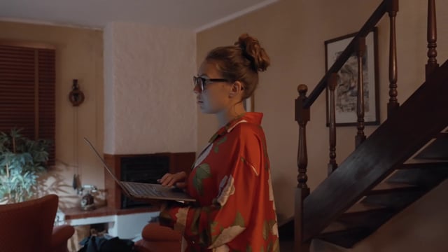 A girl walking around the room holding a laptop in her hands - Free ...