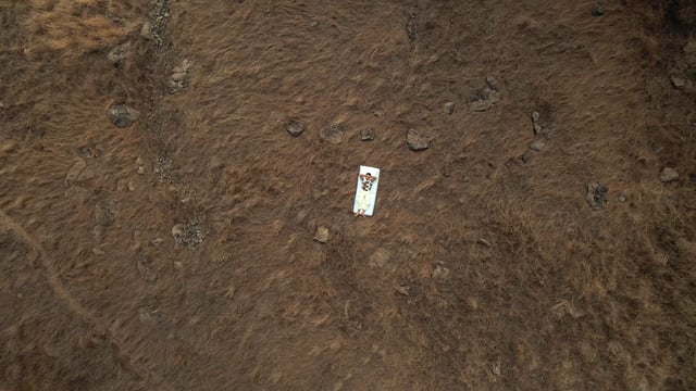 A guy is lying on a bed on the ground in the middle of a field - Free ...