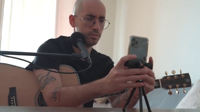 A guy setting up his phone camera to record his music performance ...